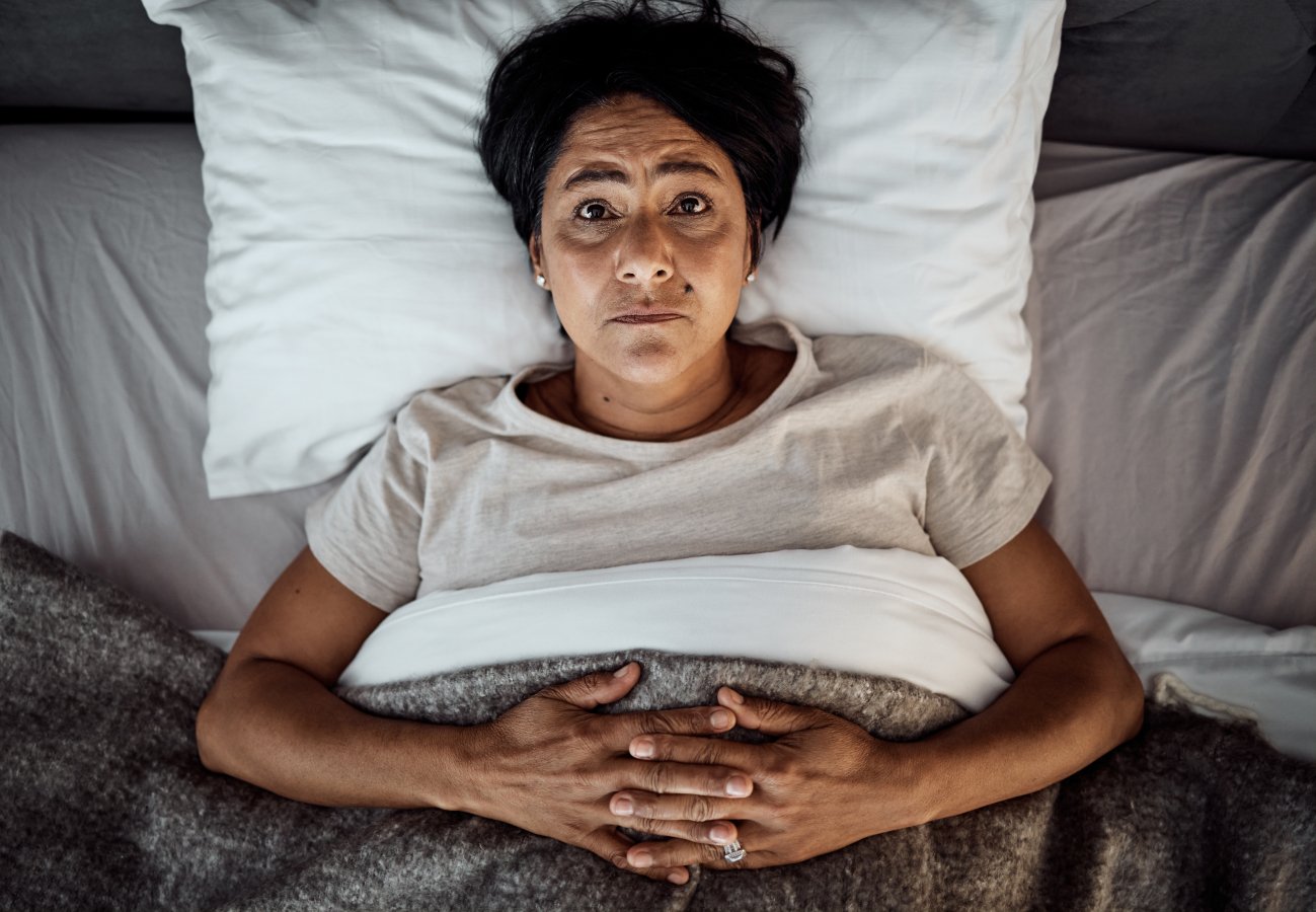 A woman in bed struggling to sleep.
